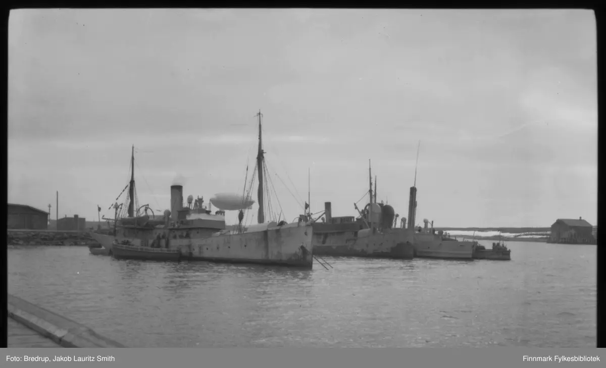 Dampskip på Vadsø havn, i bakgrunnen mellom dem ser vi et luftskip ...